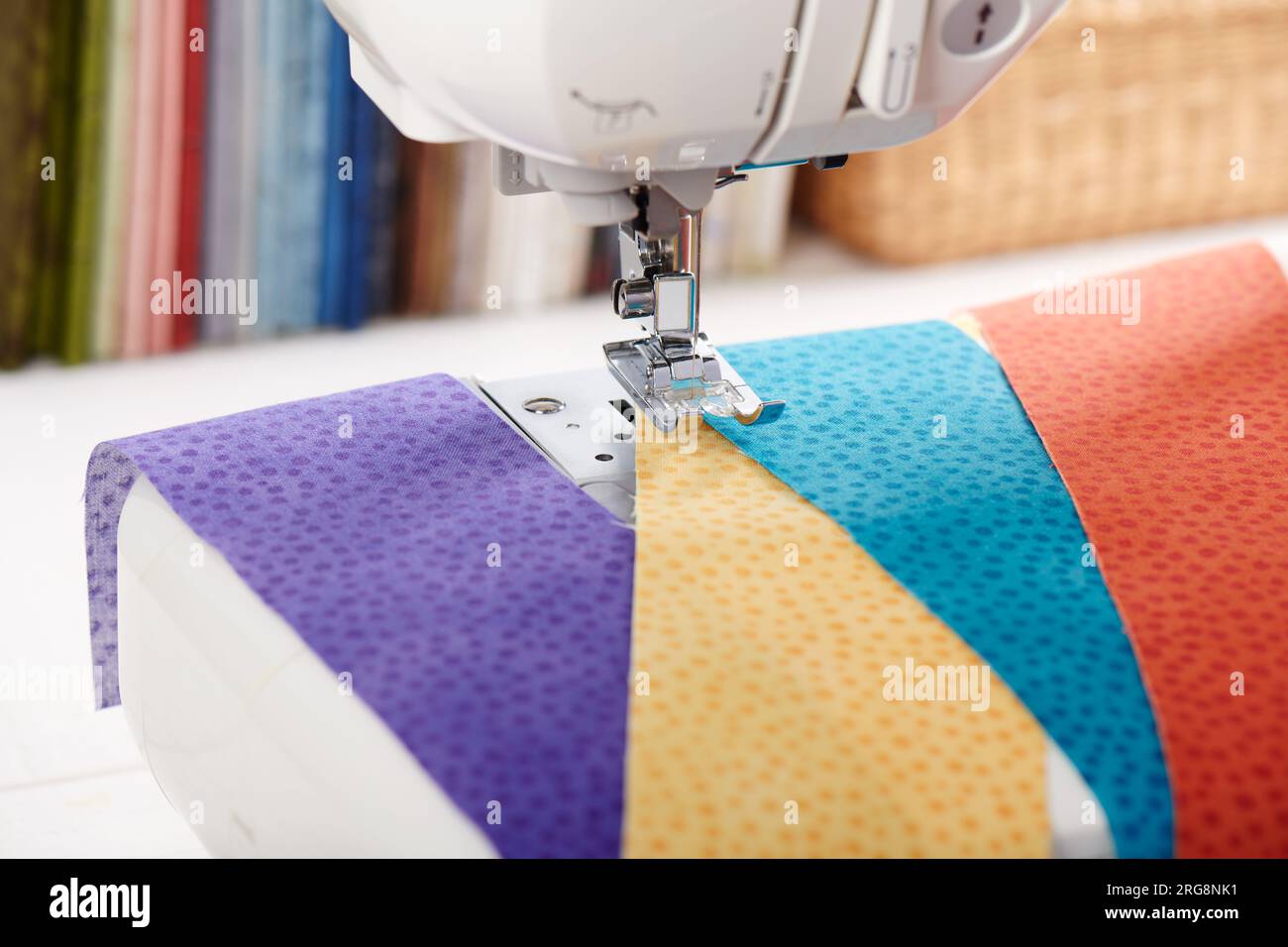 Sewing machine with a strips of fabrics on the background of stack of ...