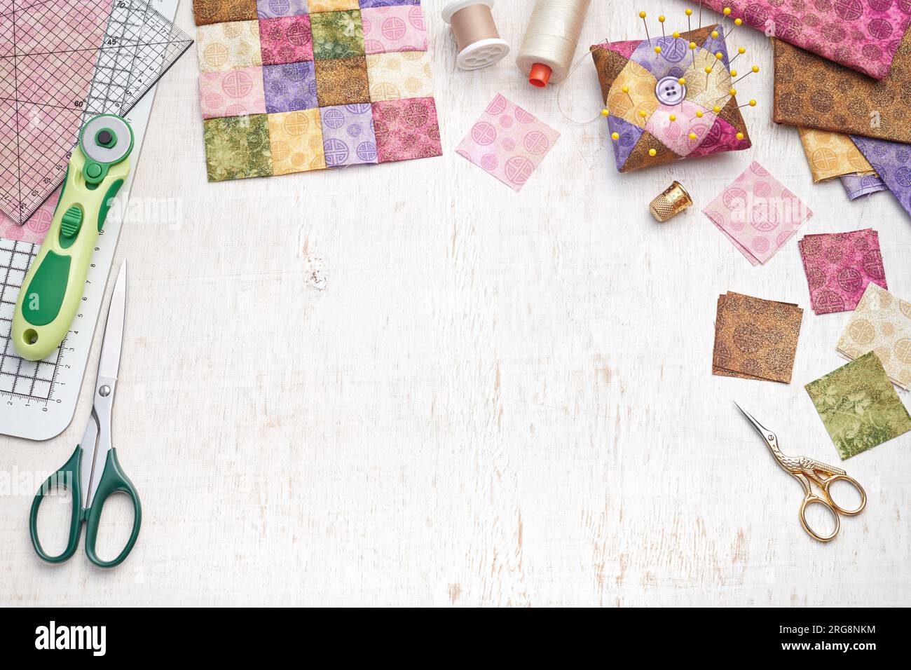 Bright square pieces of fabric, patchwork tools, sewing equipment ...