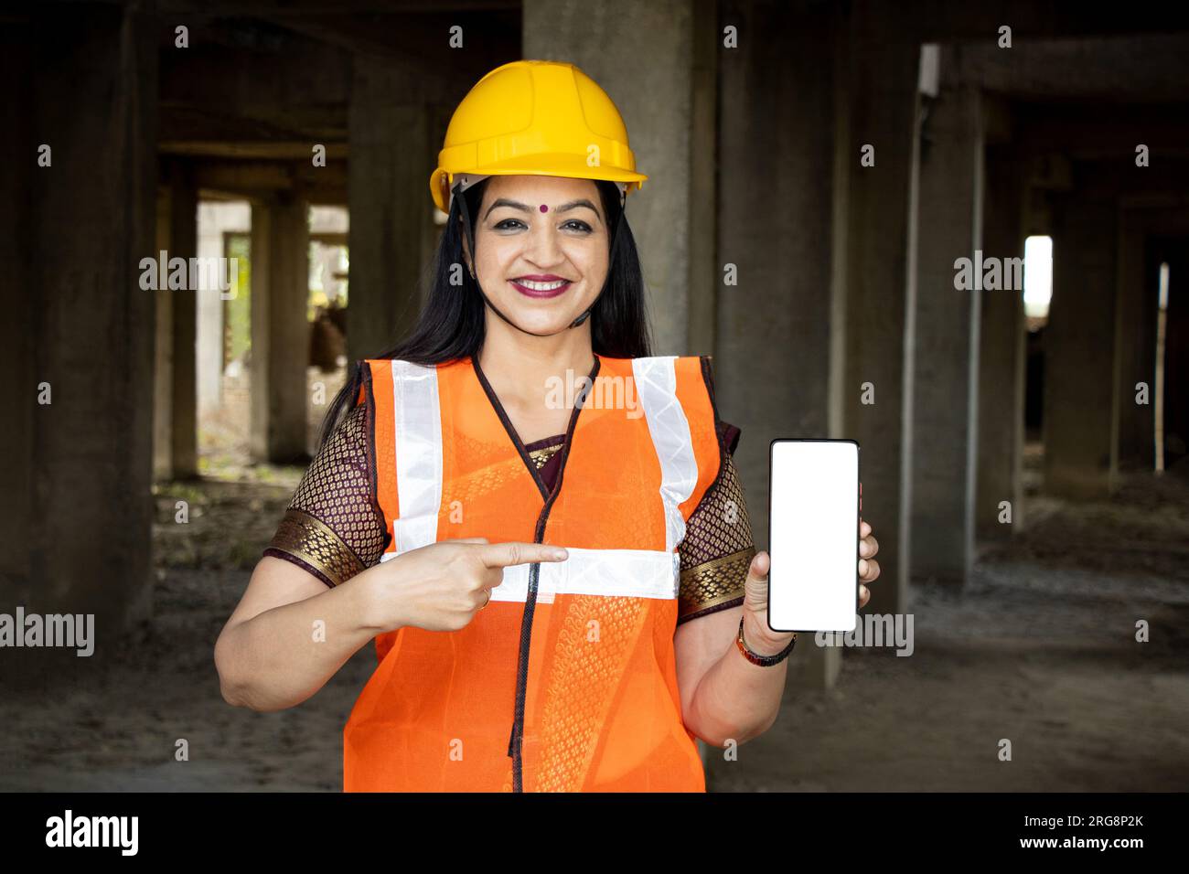 Happy Indian female civil engineer wearing helmet and vest holding ...