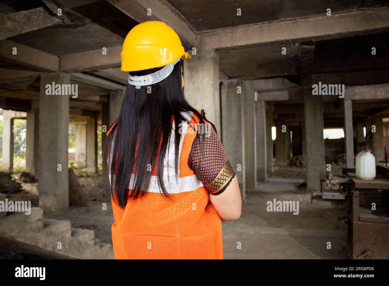 Back view of Indian female civil engineer wearing helmet and vest ...