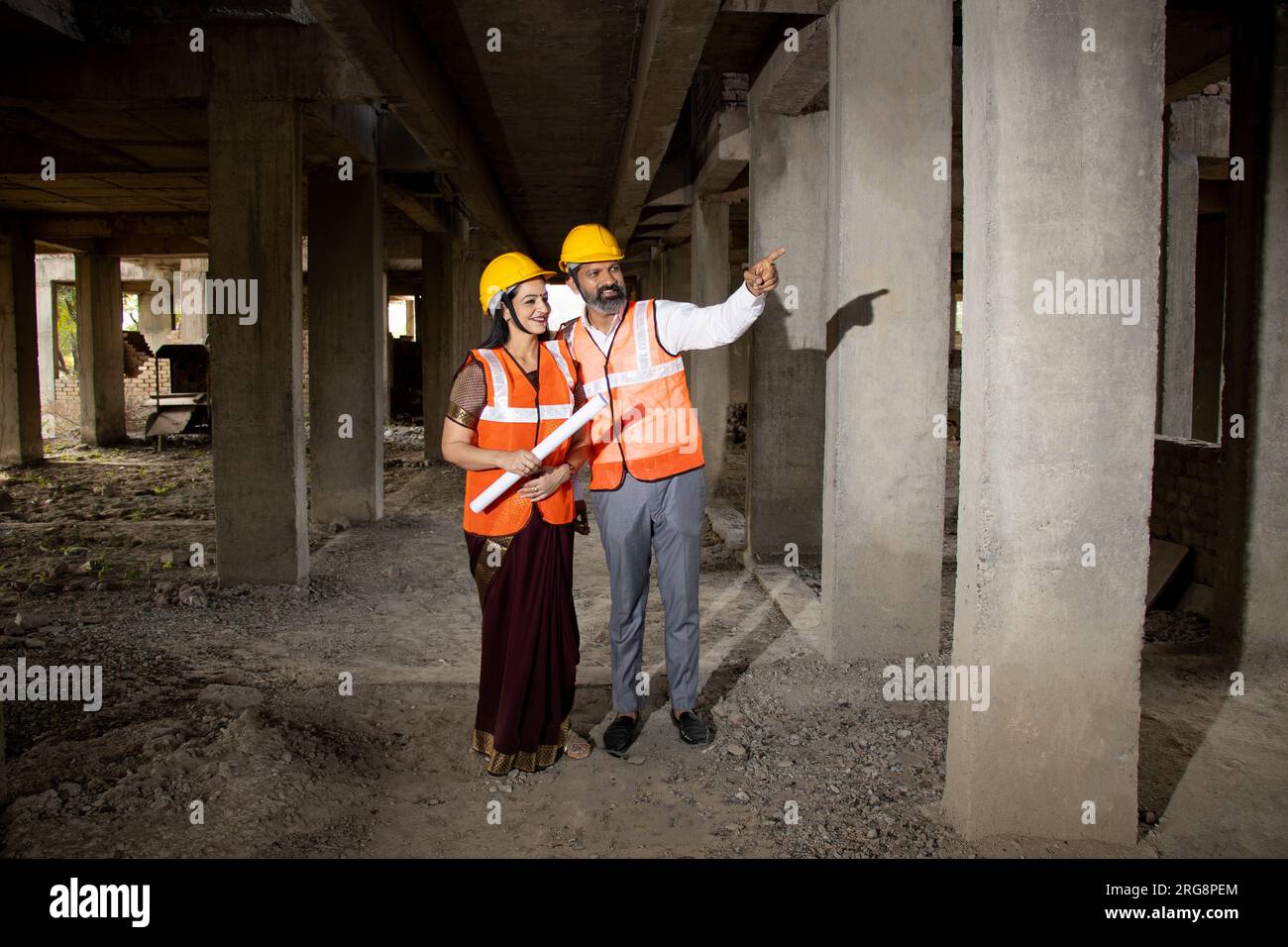Two Indian male and female civil engineers or architect wearing helmet ...