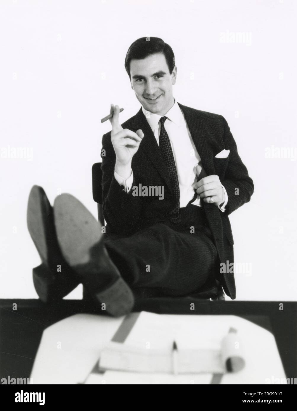 A man puts his feet up on his desk as he smokes a cigar Stock Photo - Alamy