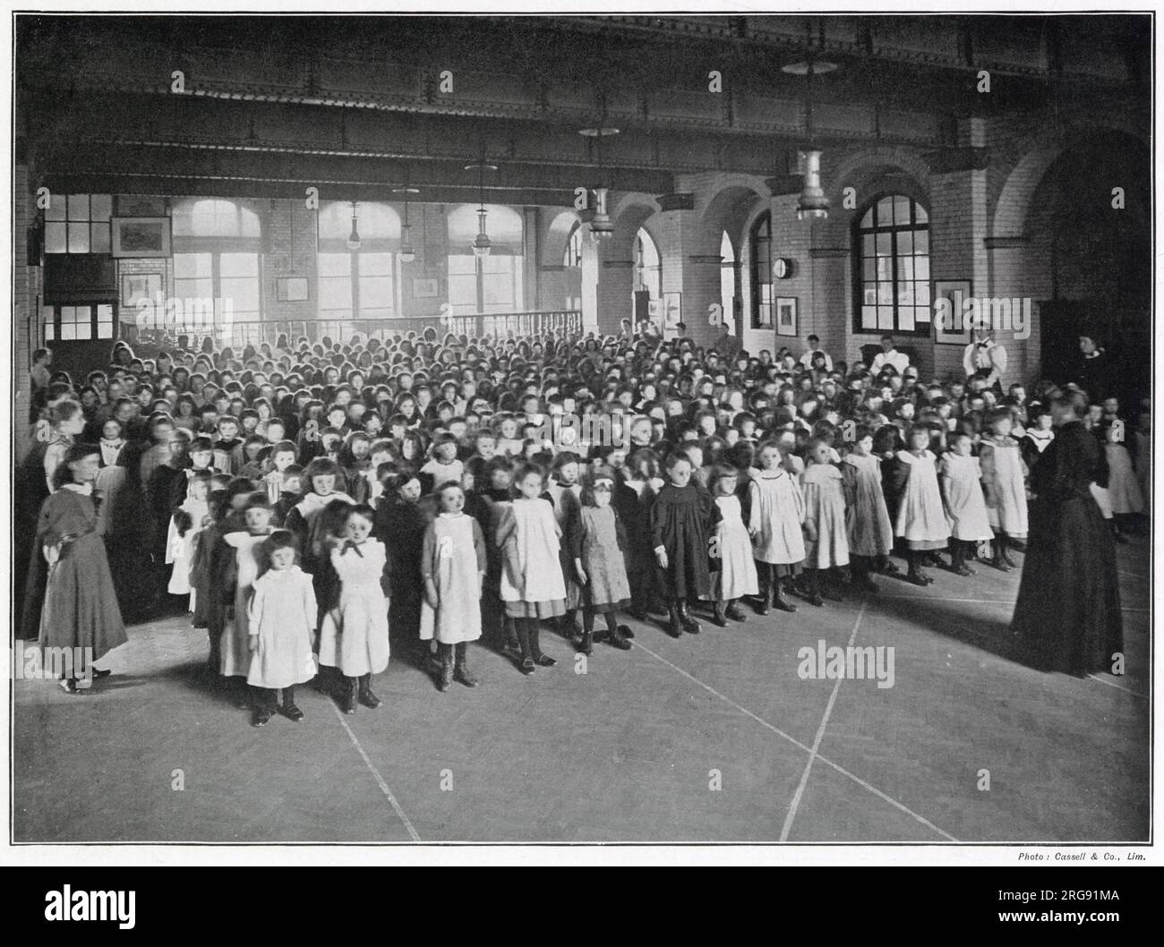 Head Mistress taking morning assembly, with girls standing-up in rows ...