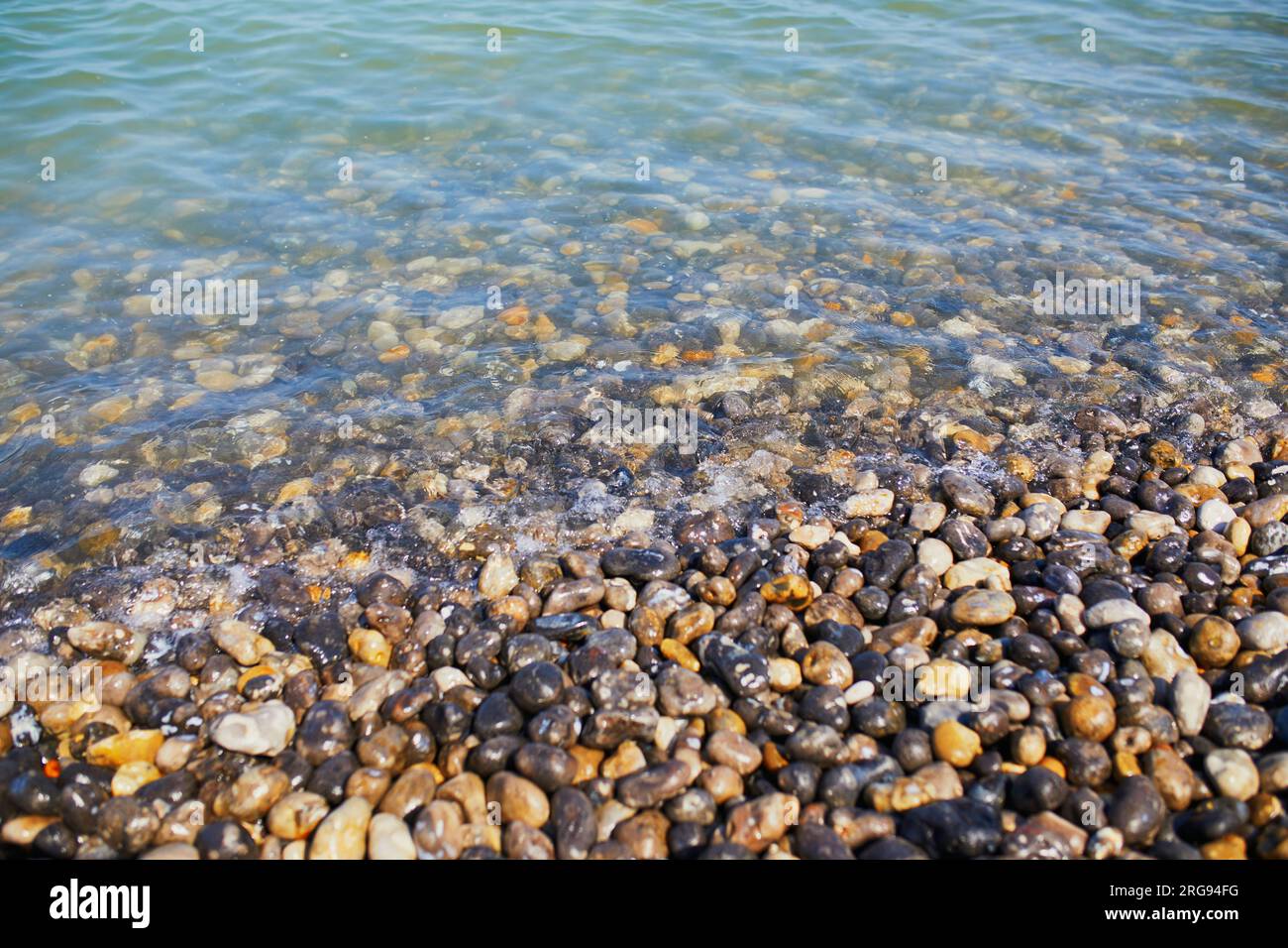 Clear blue water and and pebbles on a beach at Atlantic coast at ...