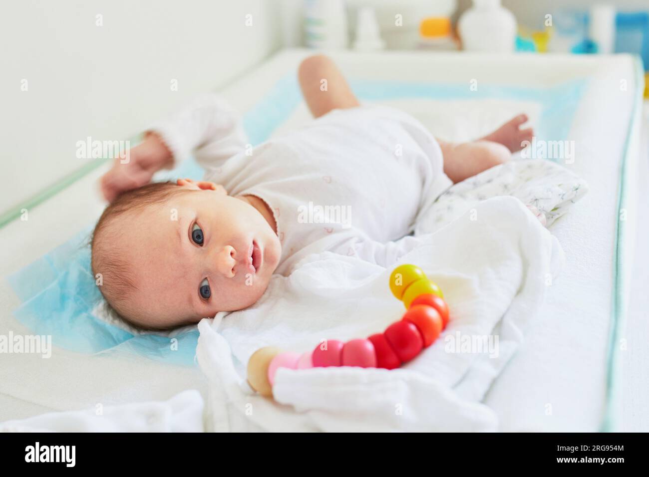 Newborn baby girl lying on changing table with wooden toy Stock Photo ...