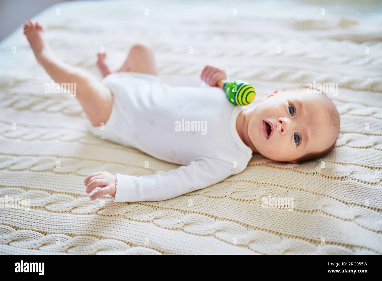 Newborn baby girl playing with colorful rattle toy. Development games ...