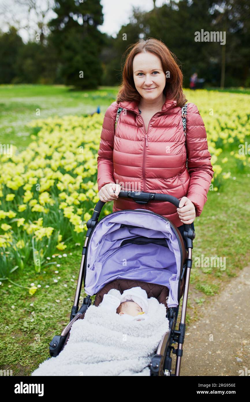 Happy young woman walking her little baby outdoors. Mother with child in pram or stroller Stock ...