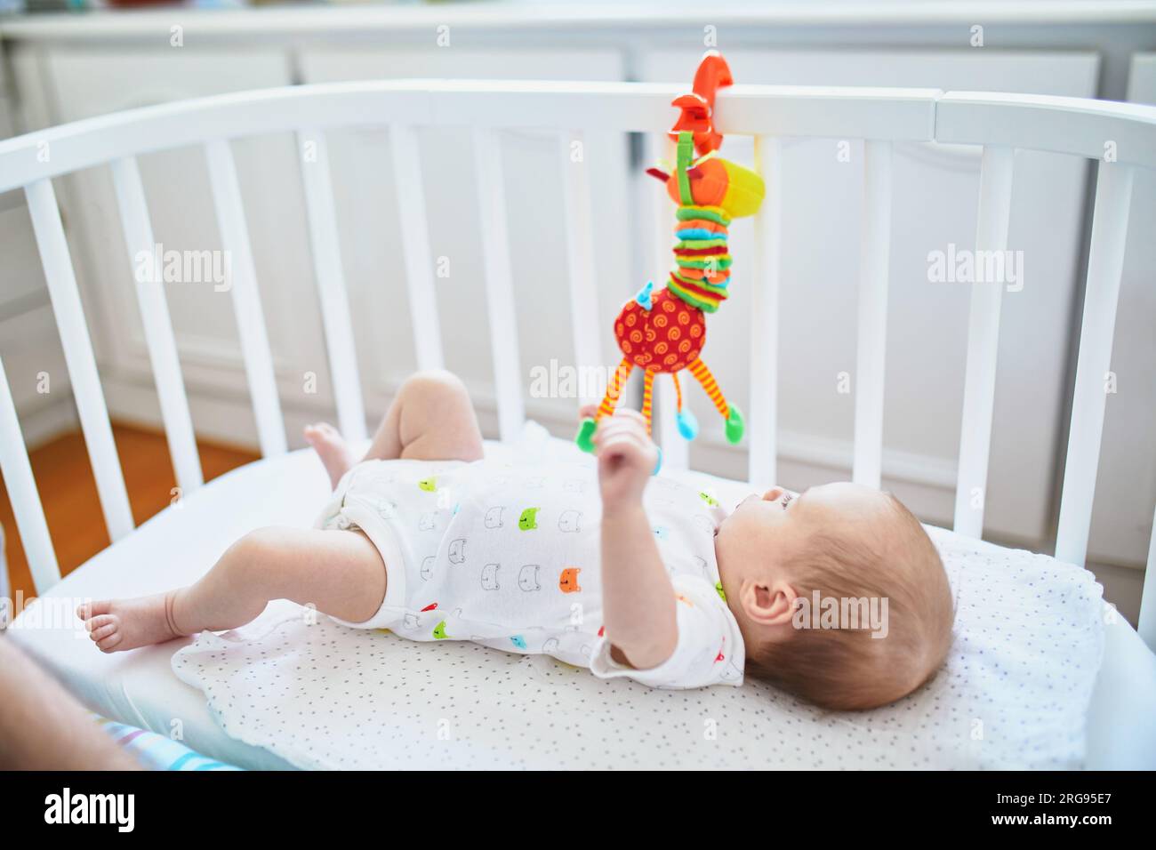 Adorable baby girl lying in the crib. Little child having a day nap in ...