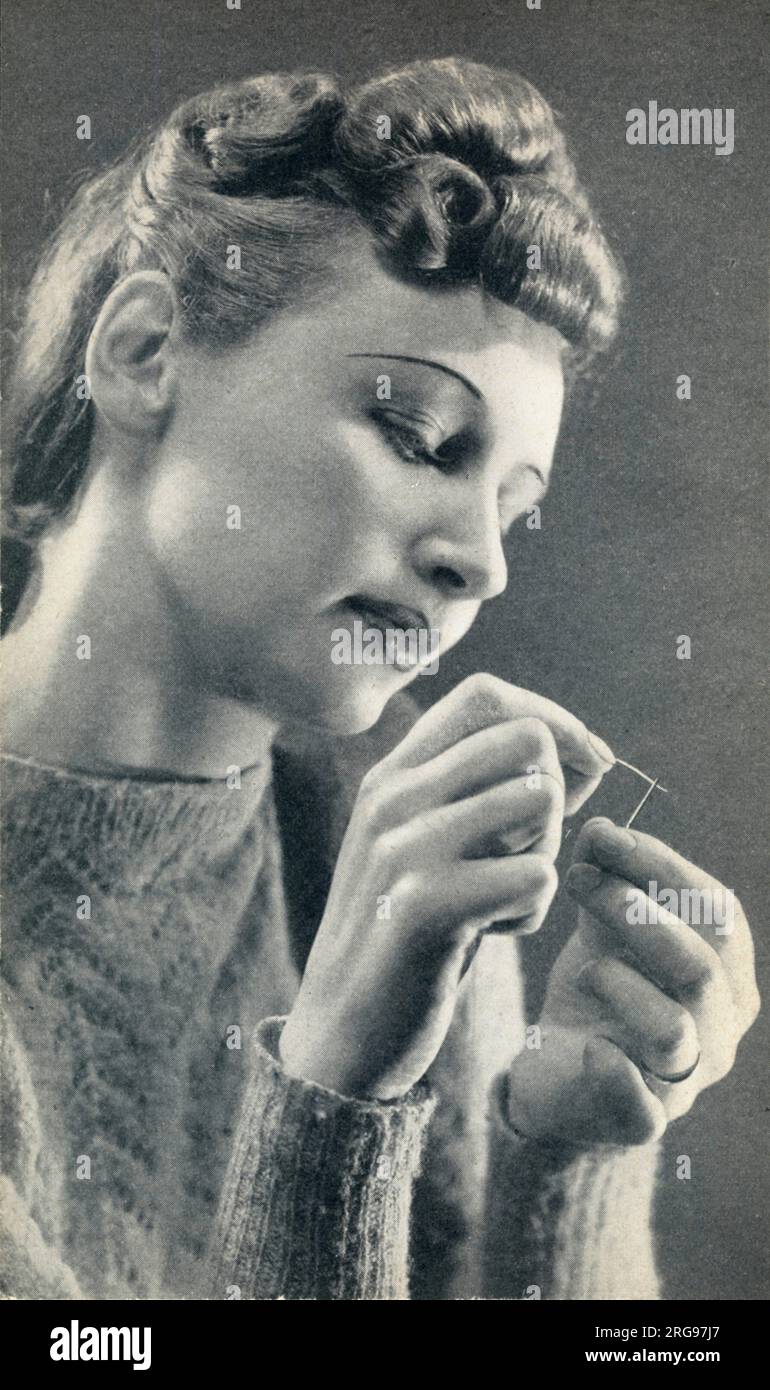 Woman threading a needle Stock Photo - Alamy