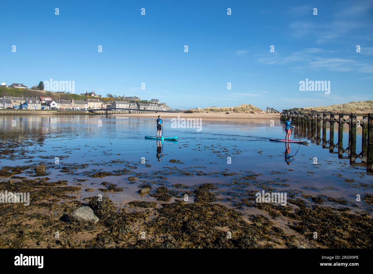 Young couple paddle boarding in the calm sea around the beach and ...