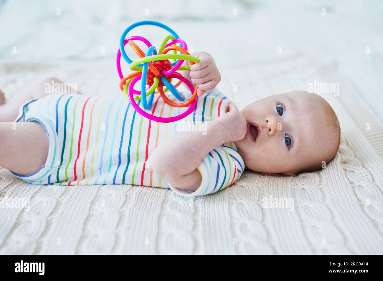 Newborn baby girl playing with colorful toy. Development games for ...