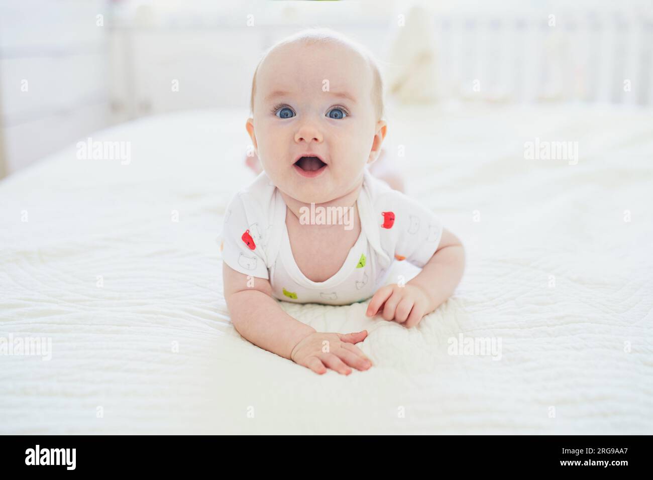 Cute baby girl lying on her tummy on bed. Happy healthy kid in nursery Stock Photo - Alamy