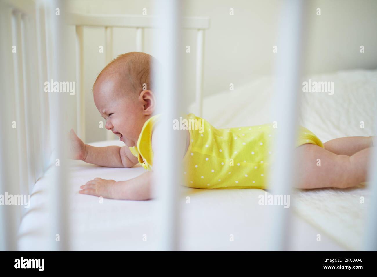 Adorable baby girl lying in co-sleeper crib attached to parents' bed ...