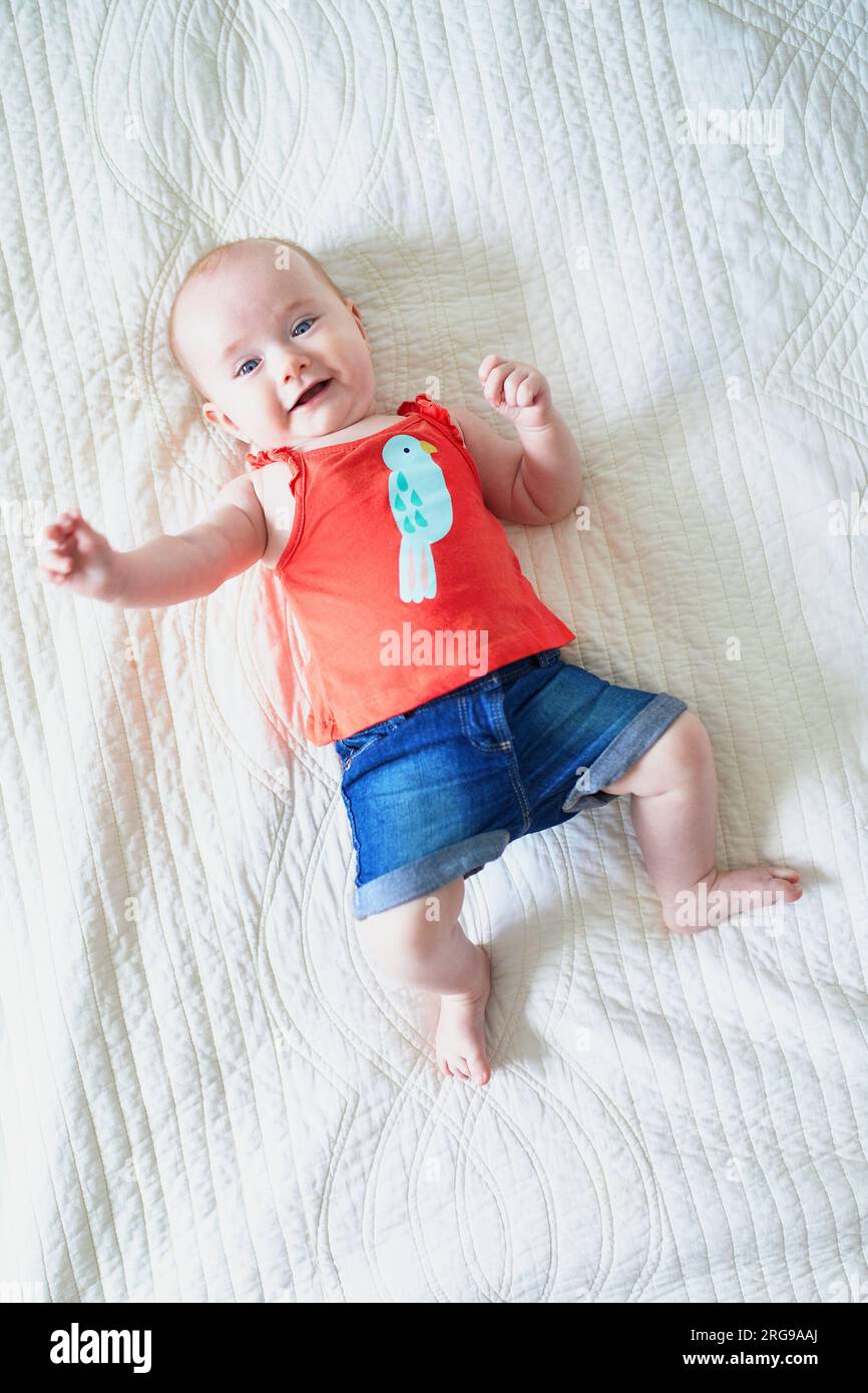 Six months old baby girl lying on her back and laughing. Happy kid ...