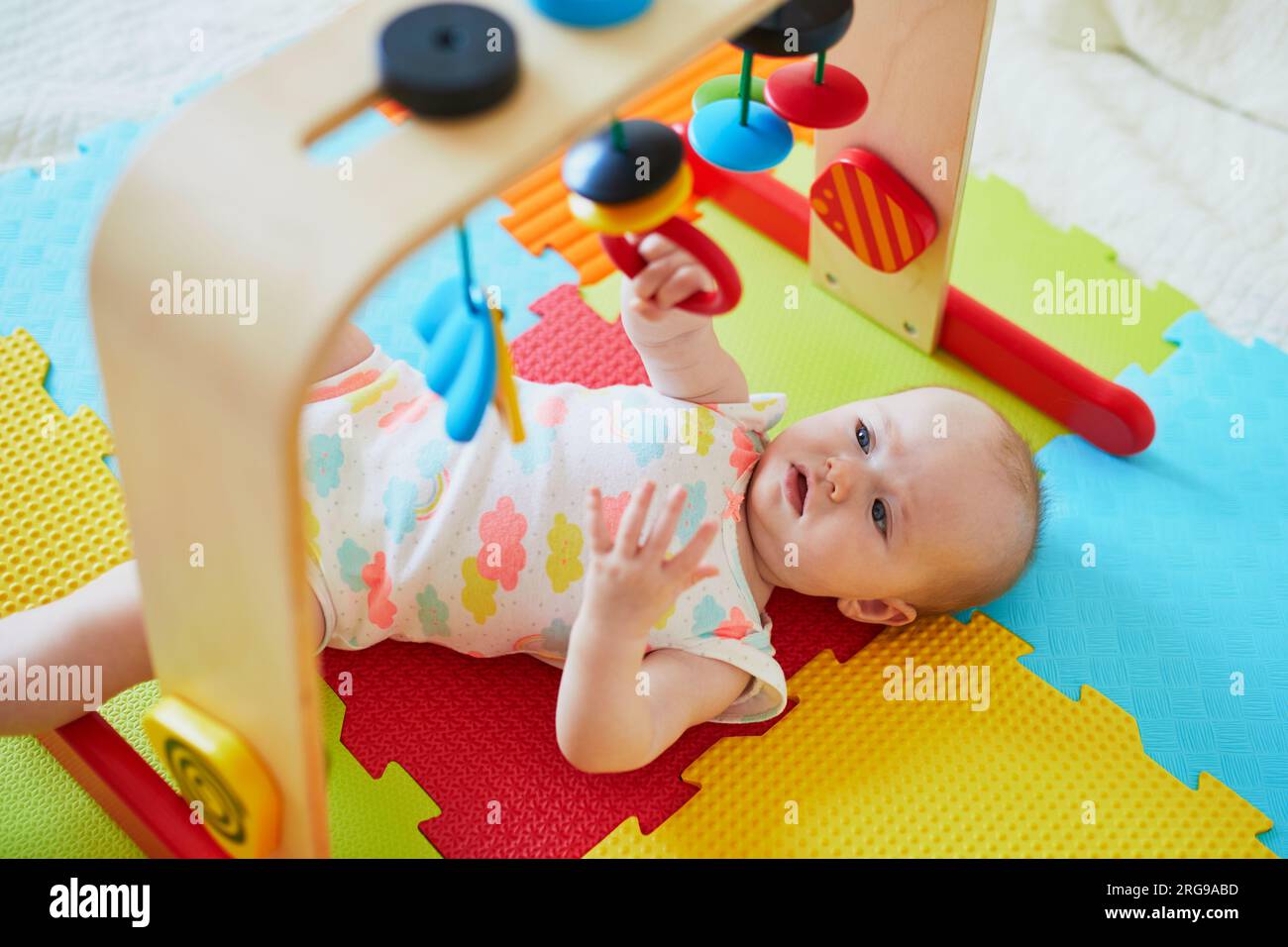 Adorable baby girl having fun with toys on colorful play mat. Happy ...