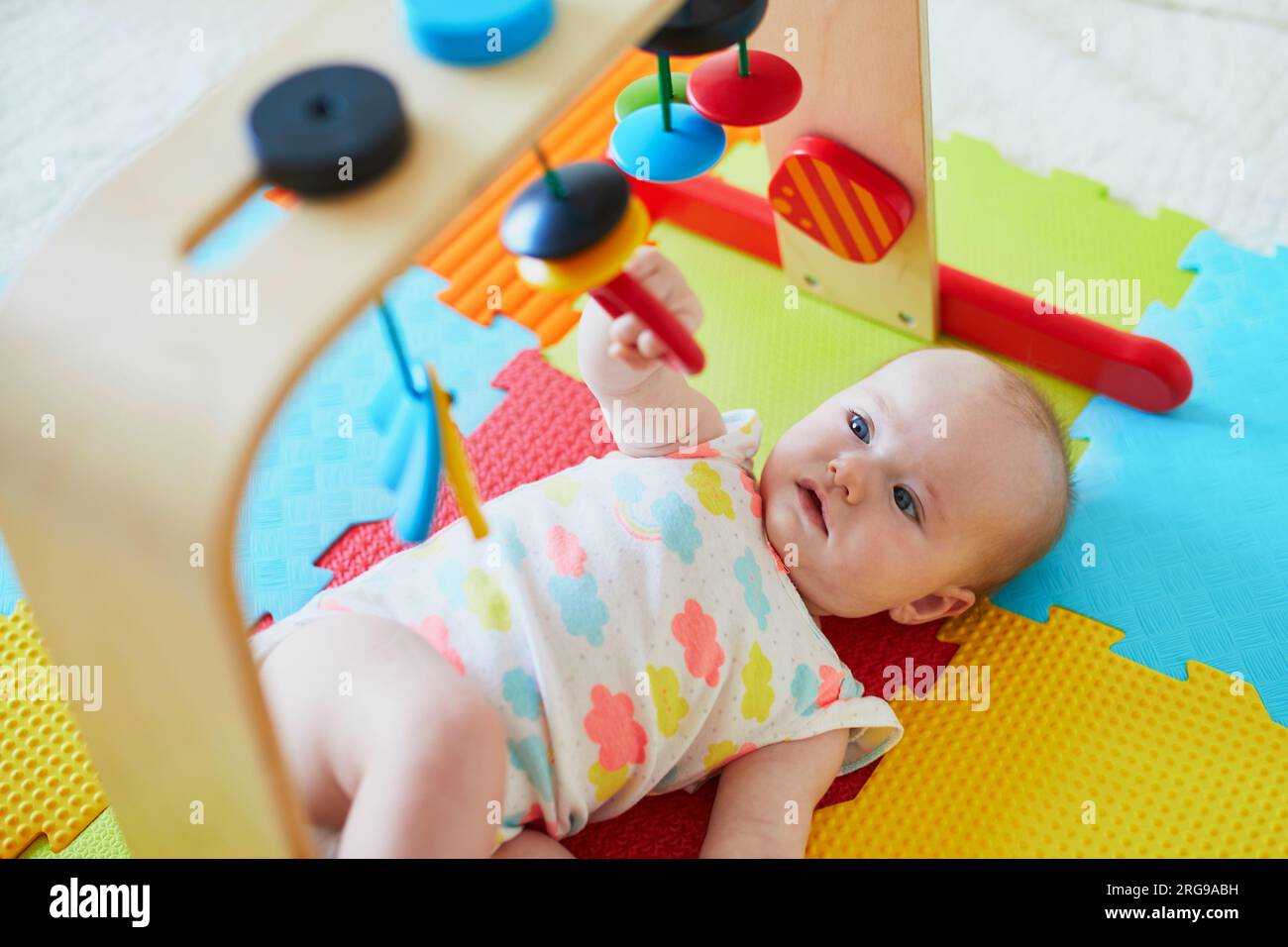Adorable baby girl having fun with toys on colorful play mat. Happy ...