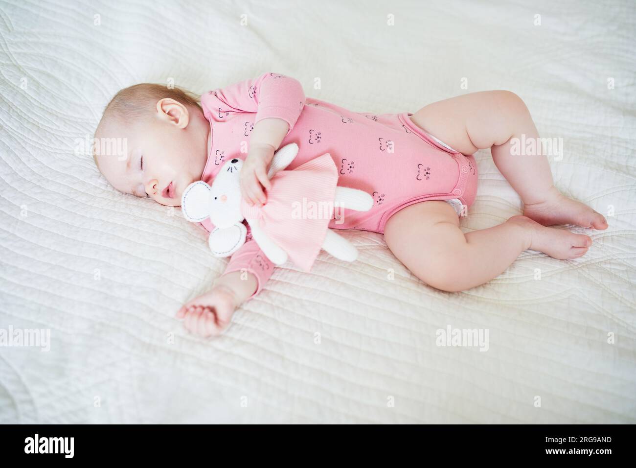 Baby girl having a nap with her favorite mouse toy. Little child ...
