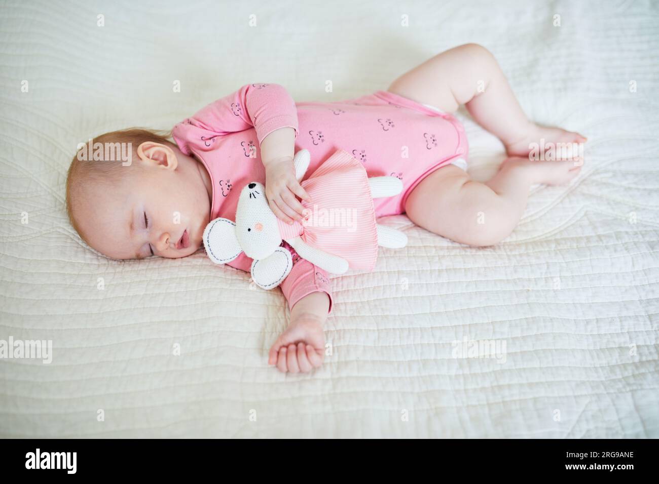 Baby girl having a nap with her favorite mouse toy. Little child ...