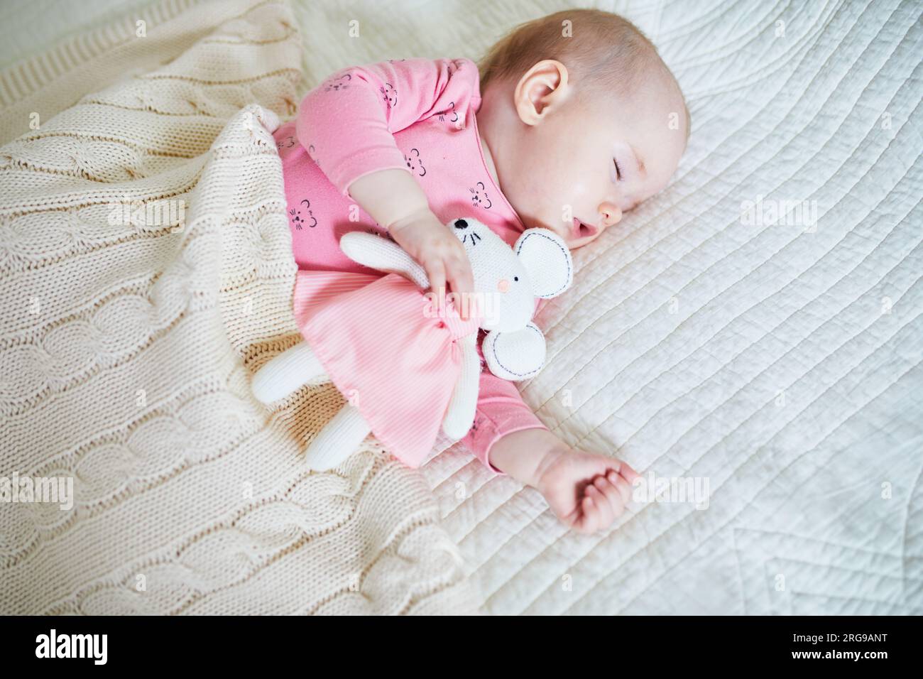 Baby girl having a nap with her favorite mouse toy. Little child ...