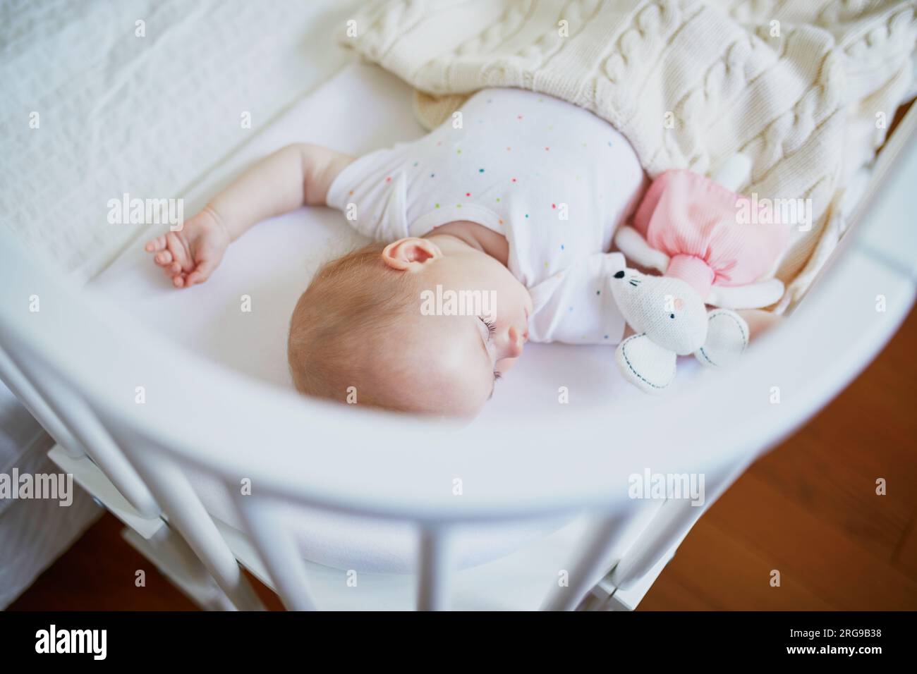 Adorable baby girl sleeping in co-sleeper crib attached to parents' bed ...