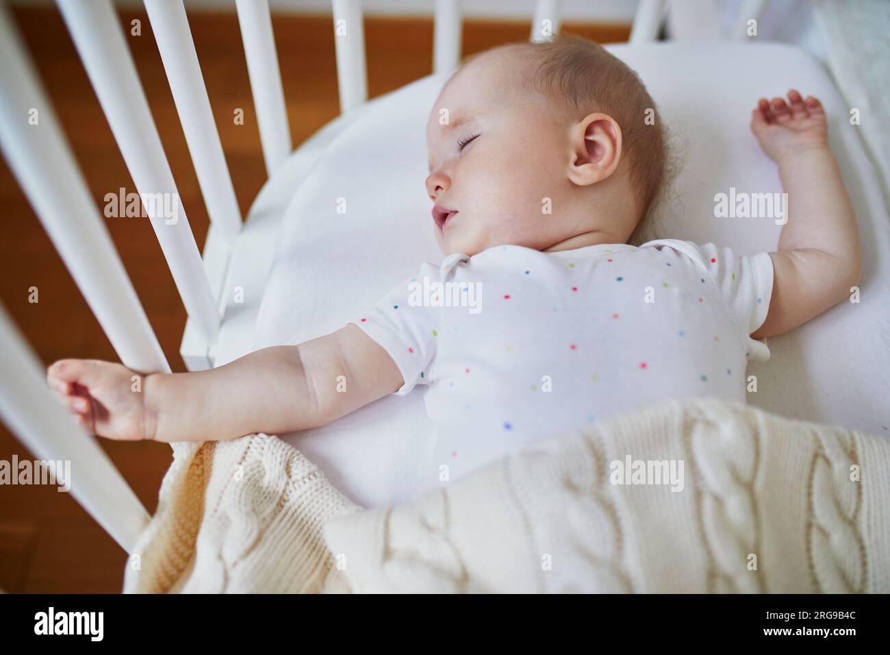 Adorable baby girl sleeping in co-sleeper crib attached to parents' bed ...