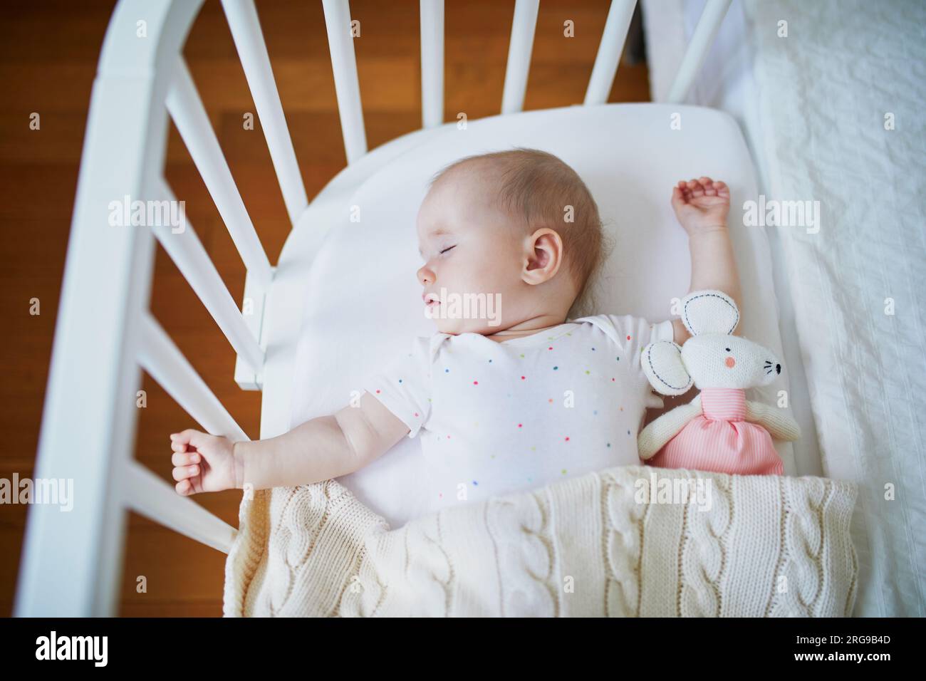 Adorable baby girl sleeping in co-sleeper crib attached to parents' bed ...