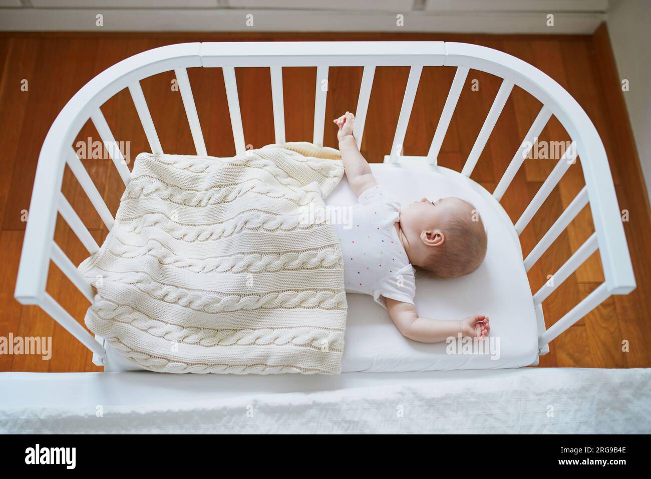 Adorable baby girl sleeping in co-sleeper crib attached to parents' bed ...