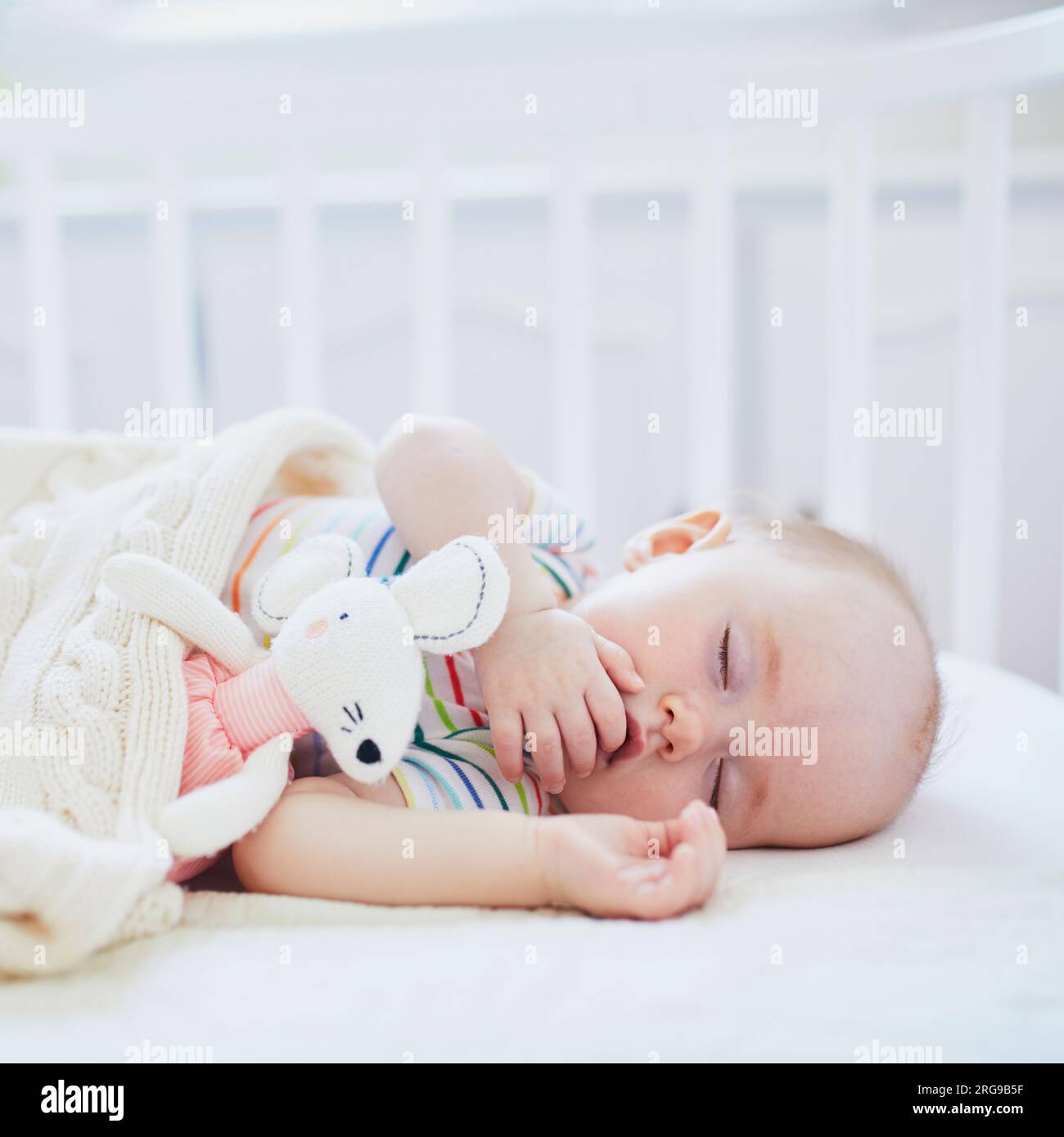 Adorable baby girl sleeping in co-sleeper crib attached to parents' bed ...
