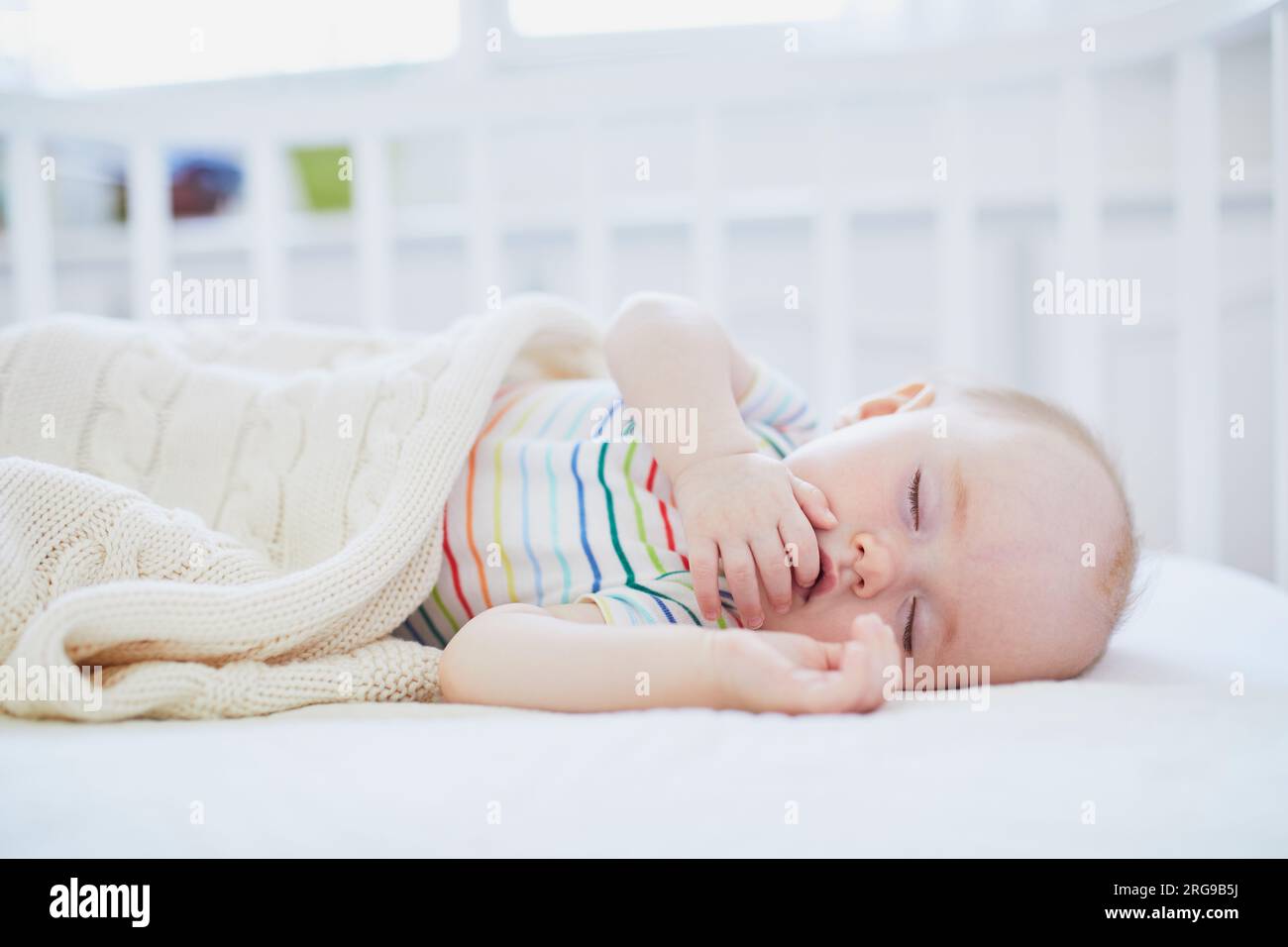 Adorable baby girl sleeping in co-sleeper crib attached to parents' bed ...