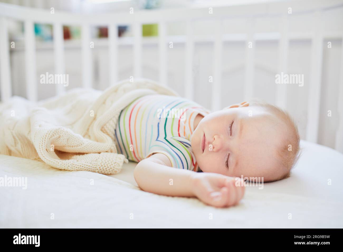 Adorable baby girl sleeping in co-sleeper crib attached to parents' bed ...