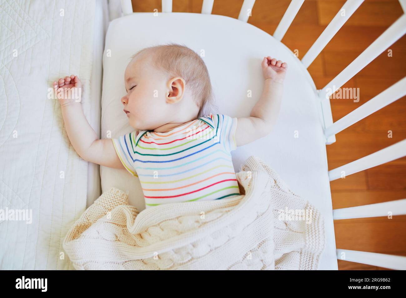 Adorable baby girl sleeping in co-sleeper crib attached to parents' bed ...