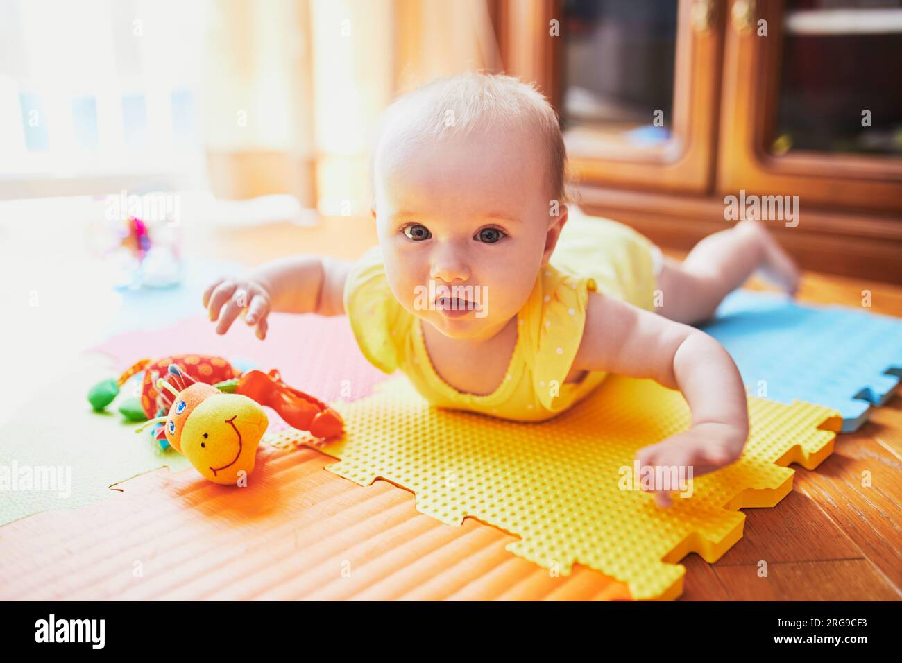 Happy smiling baby girl lying on colorful play mat on the floor Stock ...