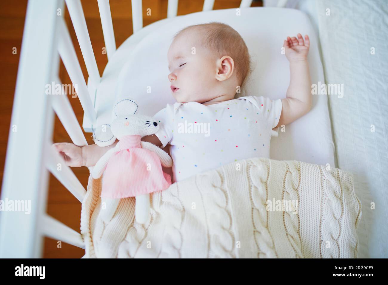 Adorable baby girl sleeping in co-sleeper crib attached to parents' bed ...