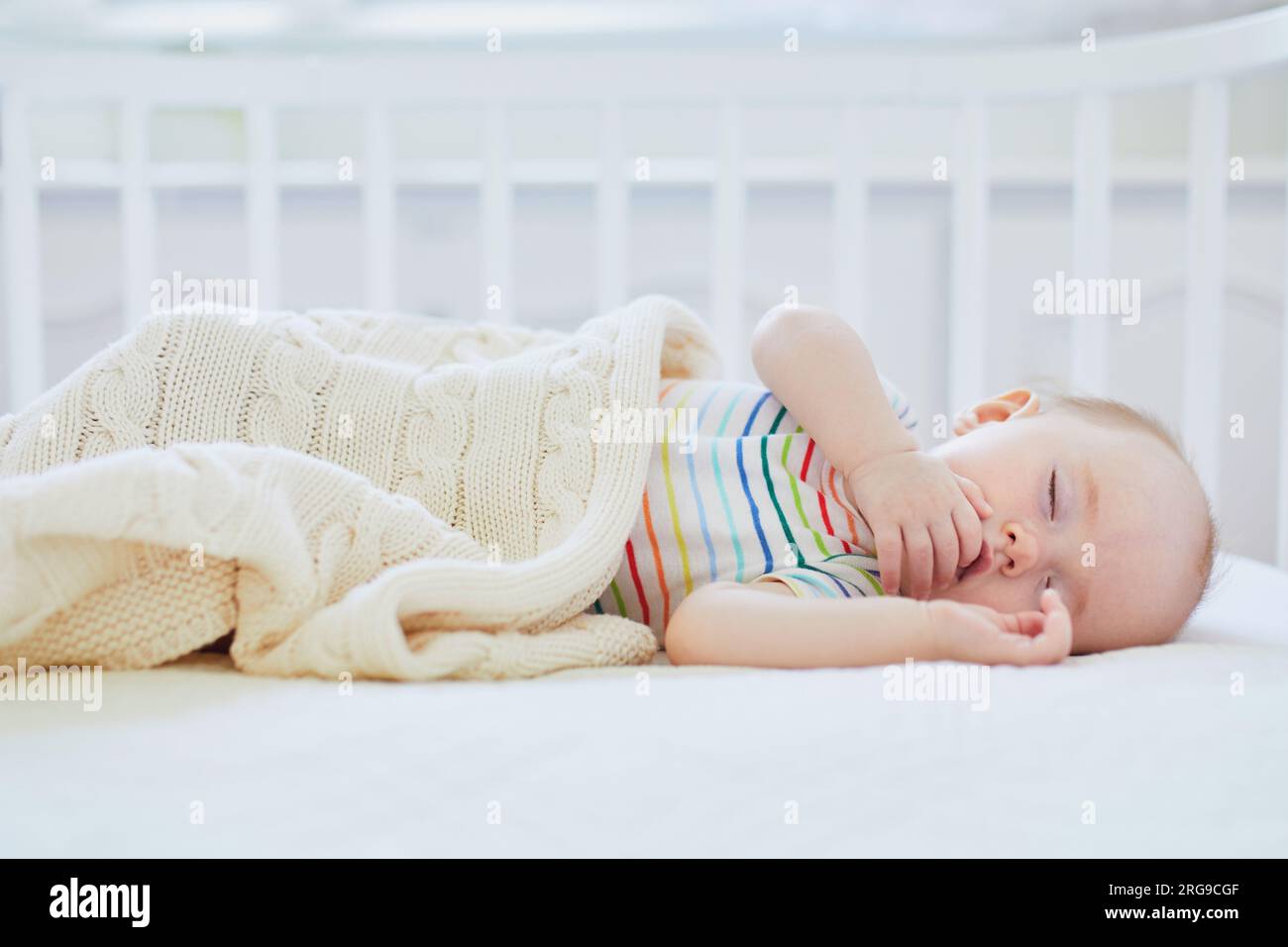 Adorable baby girl sleeping in co-sleeper crib attached to parents' bed ...
