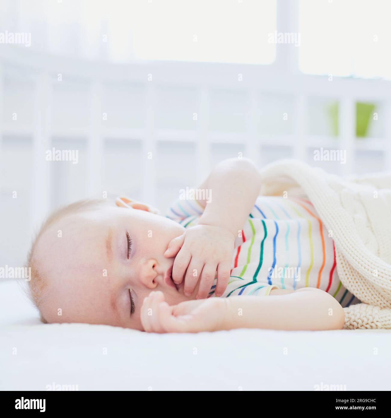 Adorable baby girl sleeping in co-sleeper crib attached to parents' bed ...