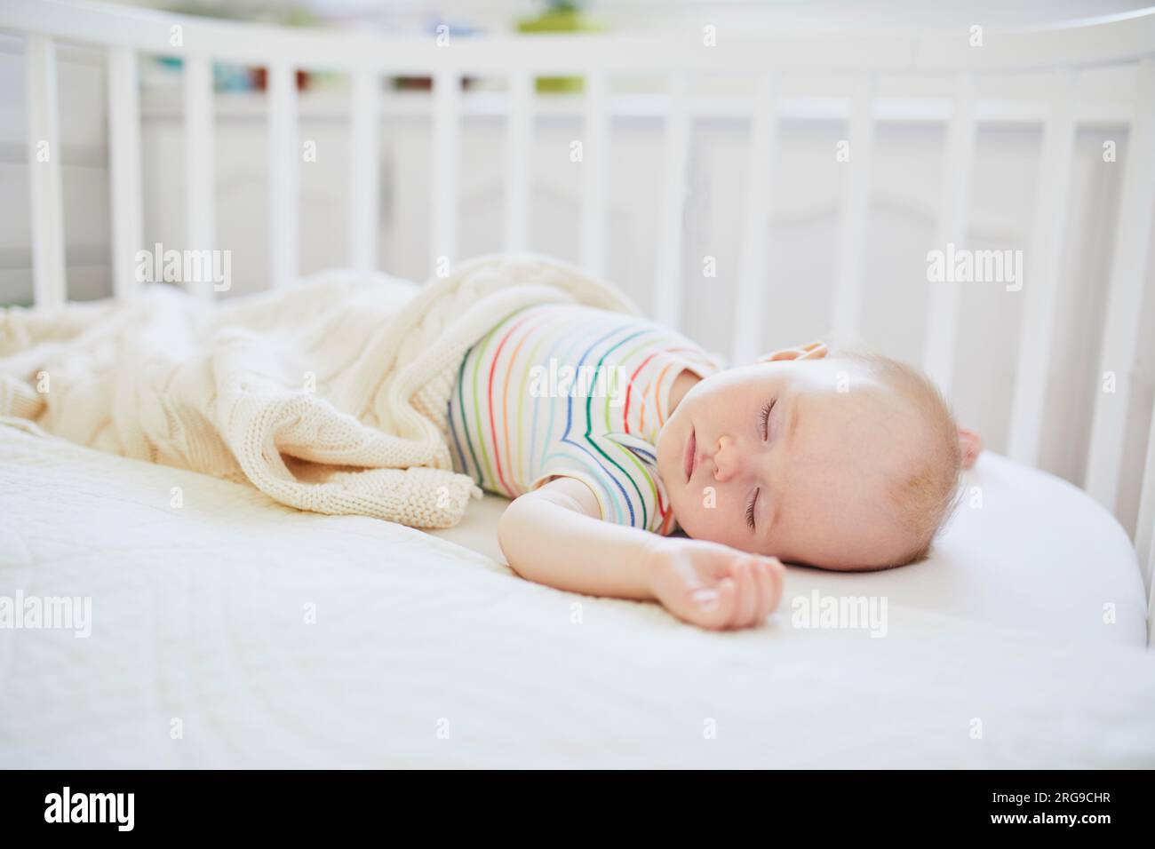 Adorable baby girl sleeping in co-sleeper crib attached to parents' bed ...