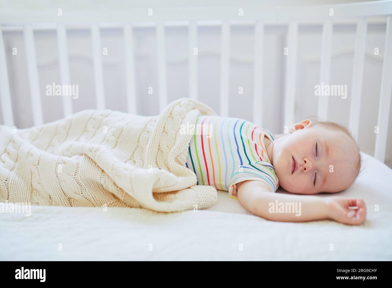 Adorable baby girl sleeping in co-sleeper crib attached to parents' bed ...