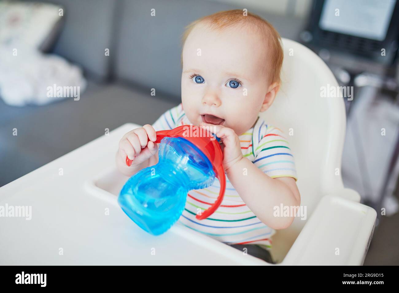 Little baby girl sitting in high chair at home or at restaurant and ...