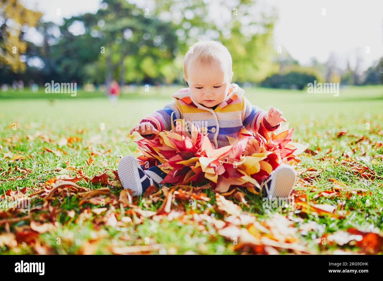 Adorable little girl sitting in large heap of colorful autumn leaves on ...