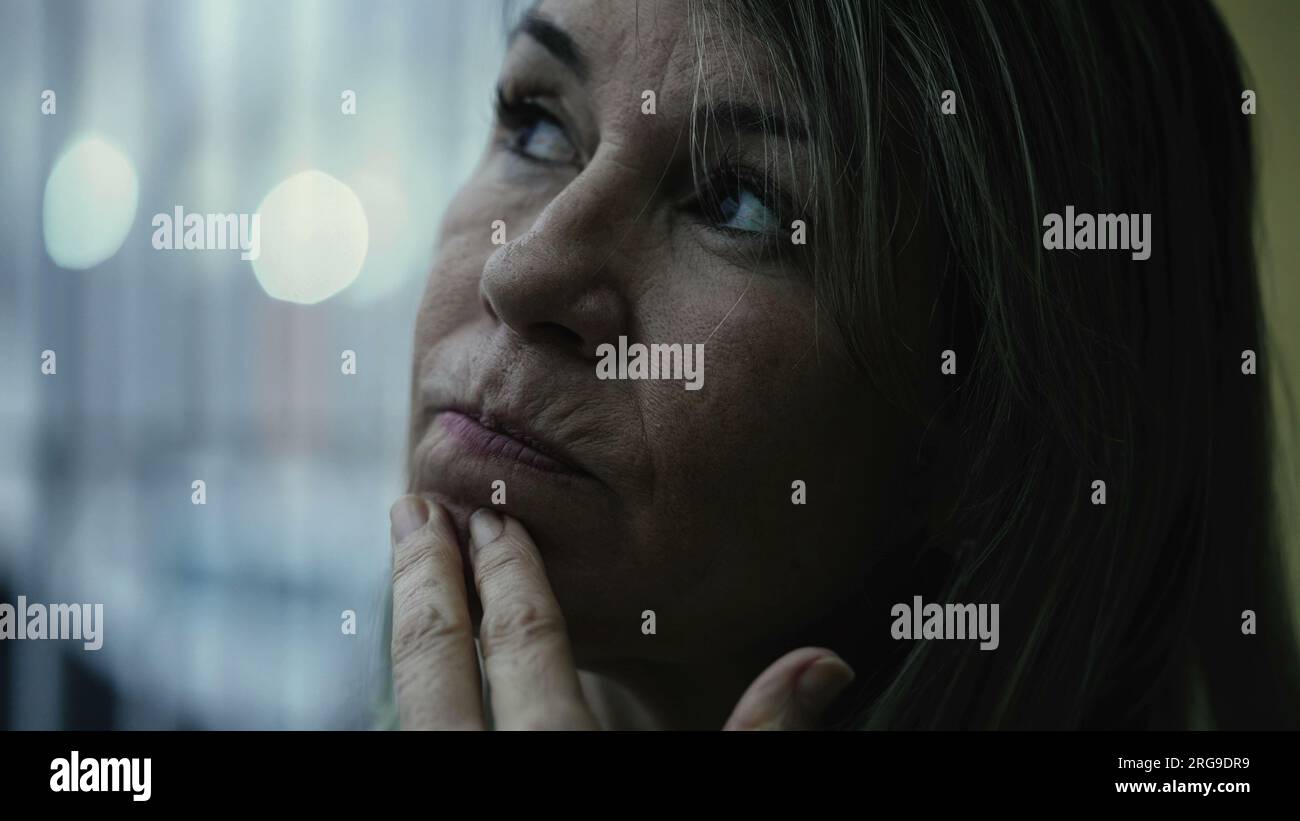 Mature woman with worried emotion, close-up face looking down in sorrow ...