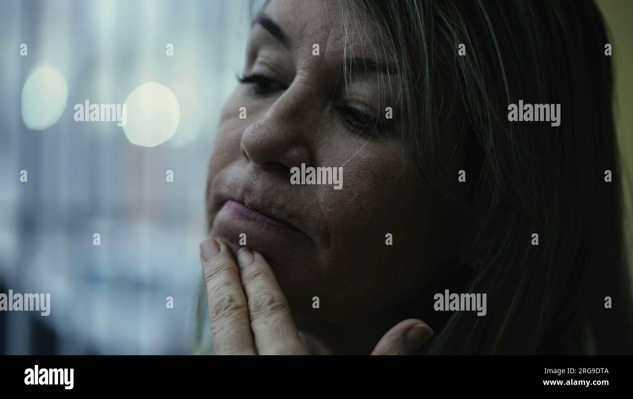 Mature woman with worried emotion, close-up face looking down in sorrow ...
