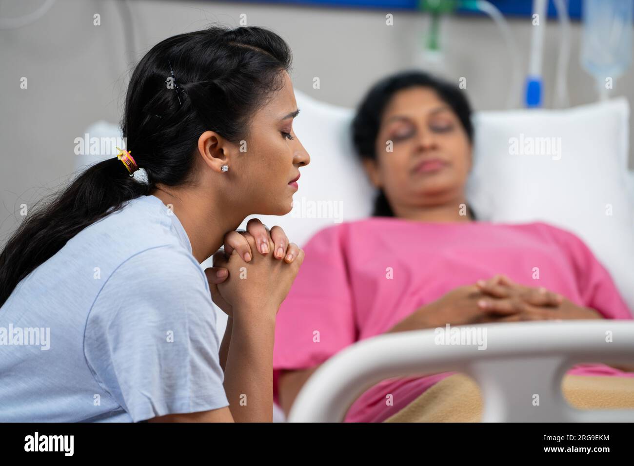 worried indian daughter praying for sick admitted mother for health ...