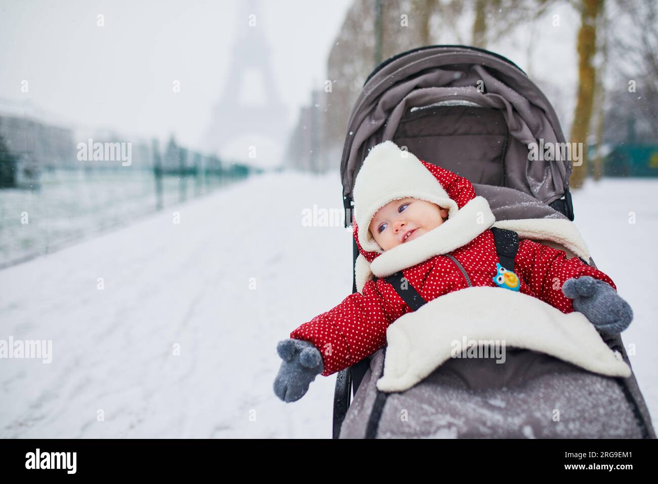 Happy smiling baby girl in stroller near the Eiffel tower on a day with ...