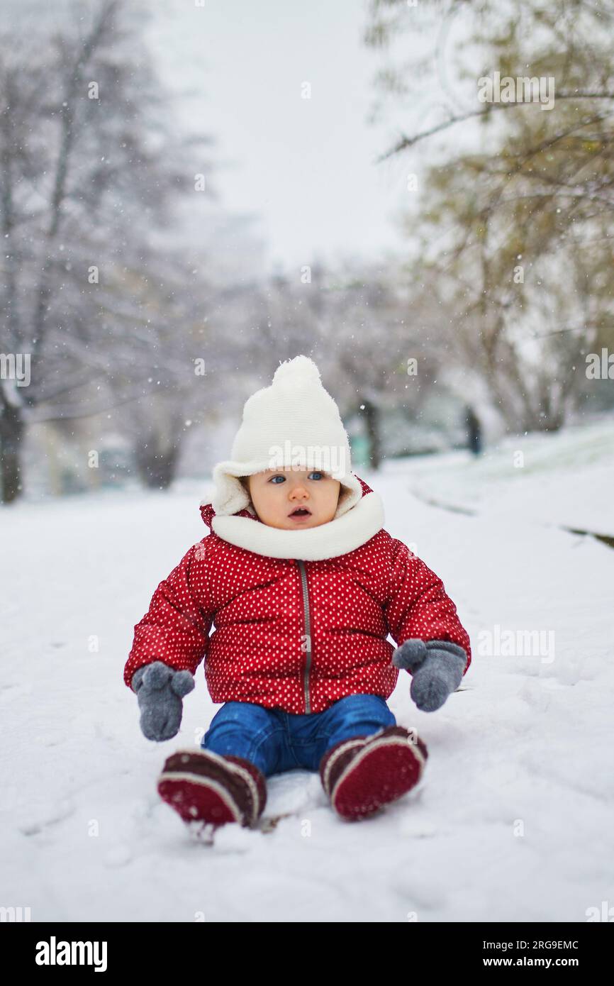 Happy smiling baby girl sitting in snow. Little kid enjoying the very ...