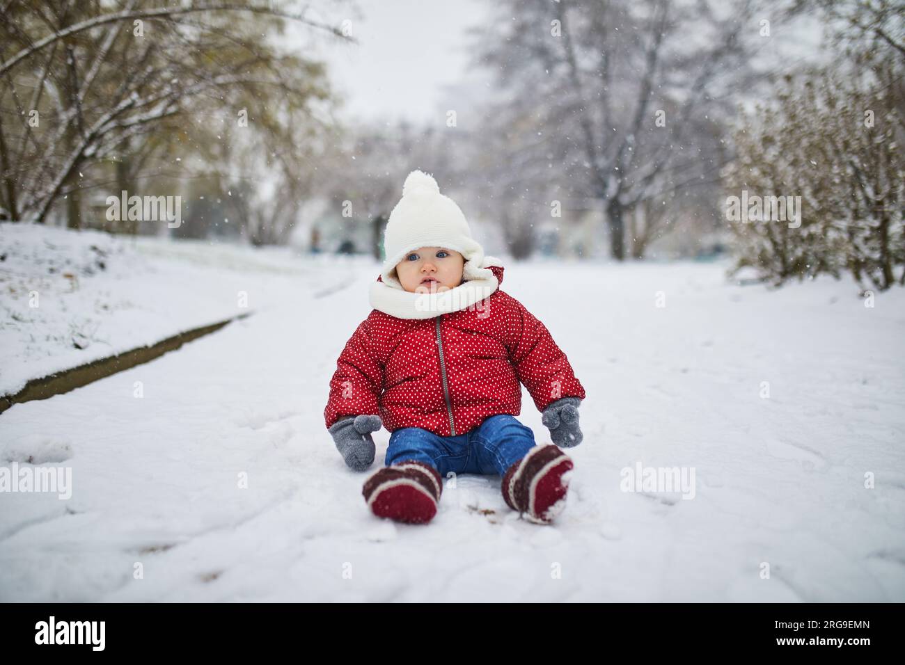 Happy smiling baby girl sitting in snow. Little kid enjoying the very ...