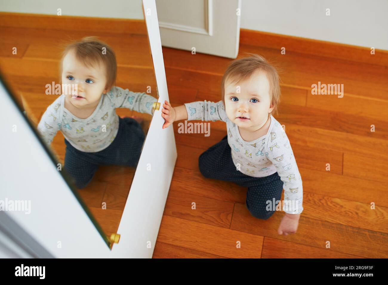 Baby girl playing with her reflection in mirror. Happy healthy little ...