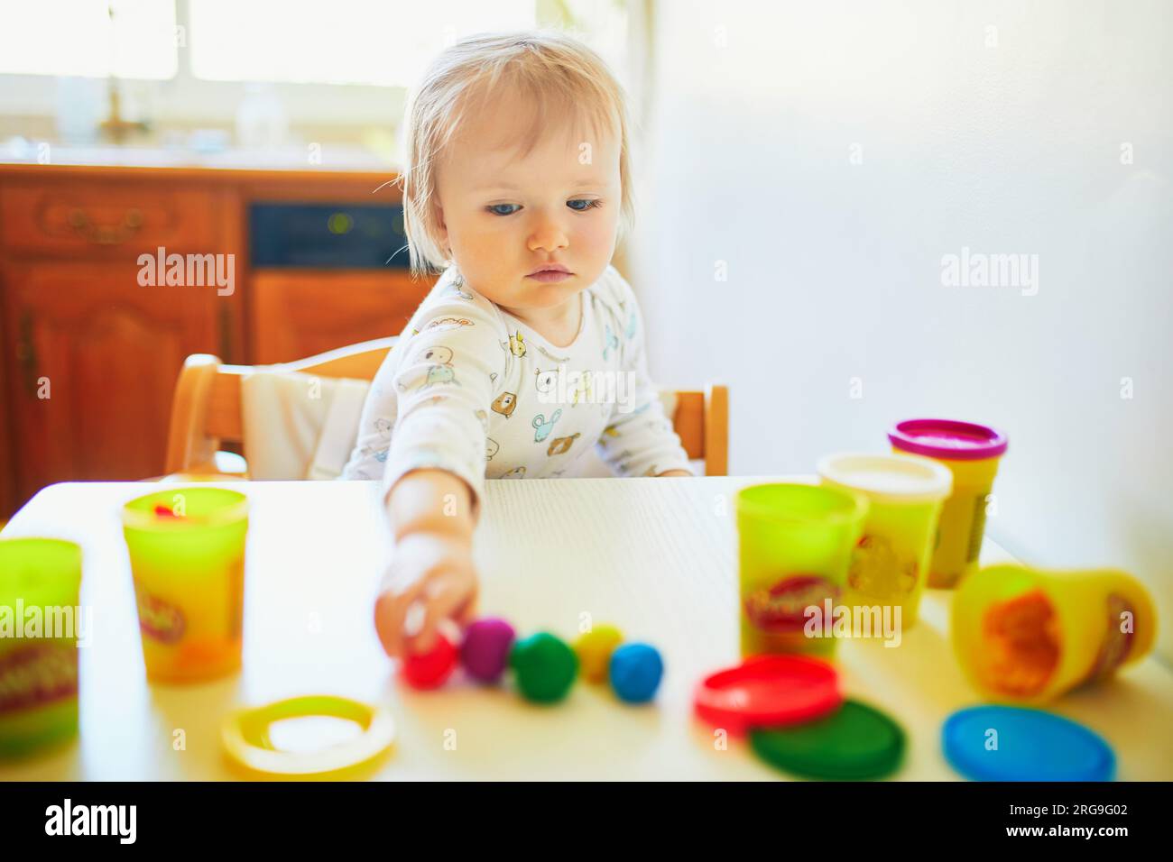 Adorable little girl playing with modelling clay at home. Toddler using ...
