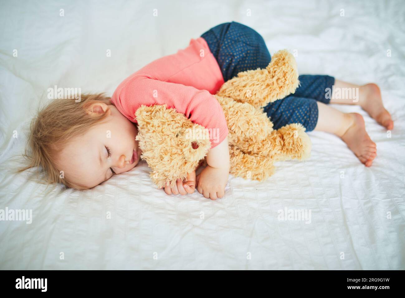 Adorable baby girl sleeping with her favorite toy. Little child having ...