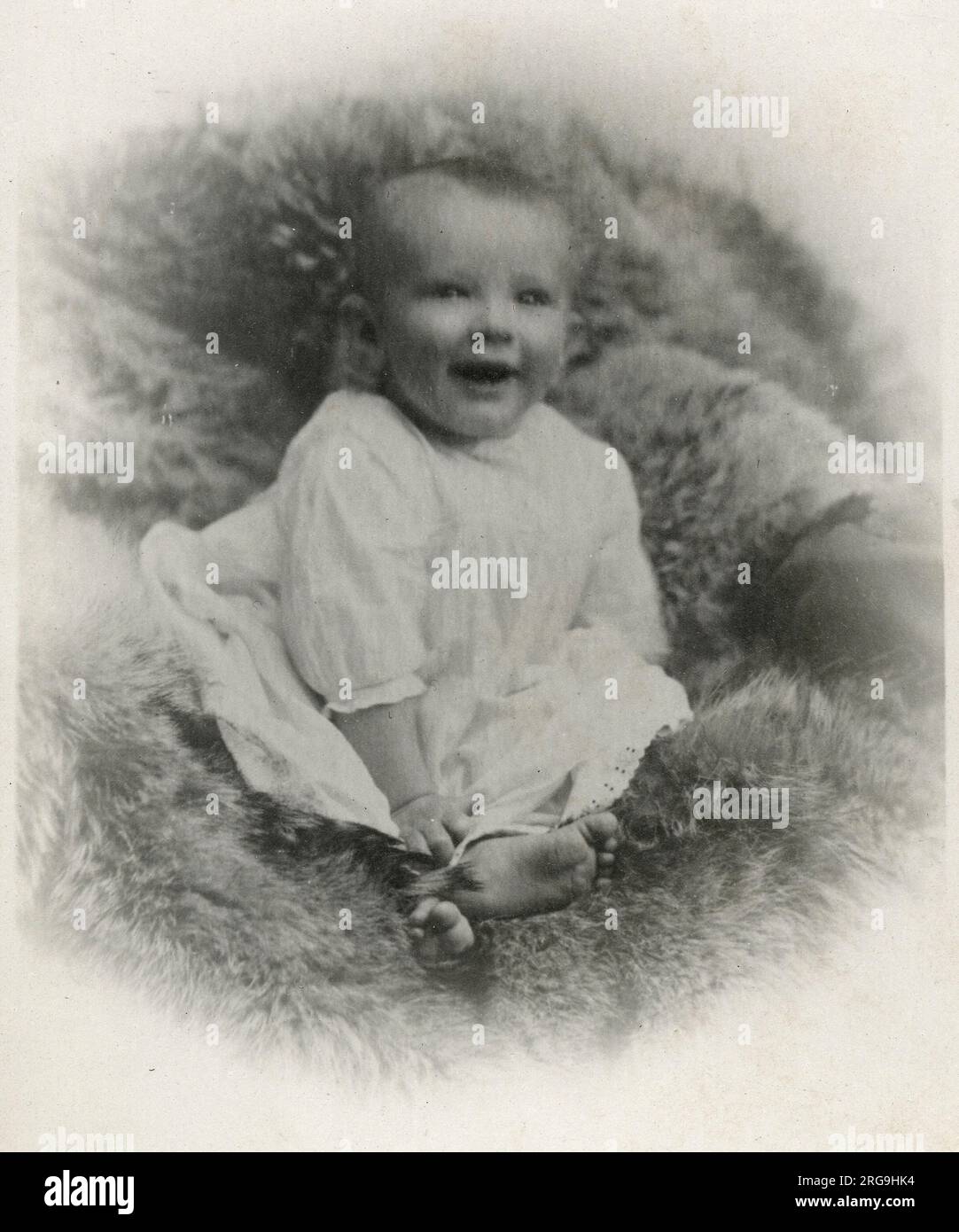 A happy young baby (Peter Fuller) sitting very comfortably on a fur ...