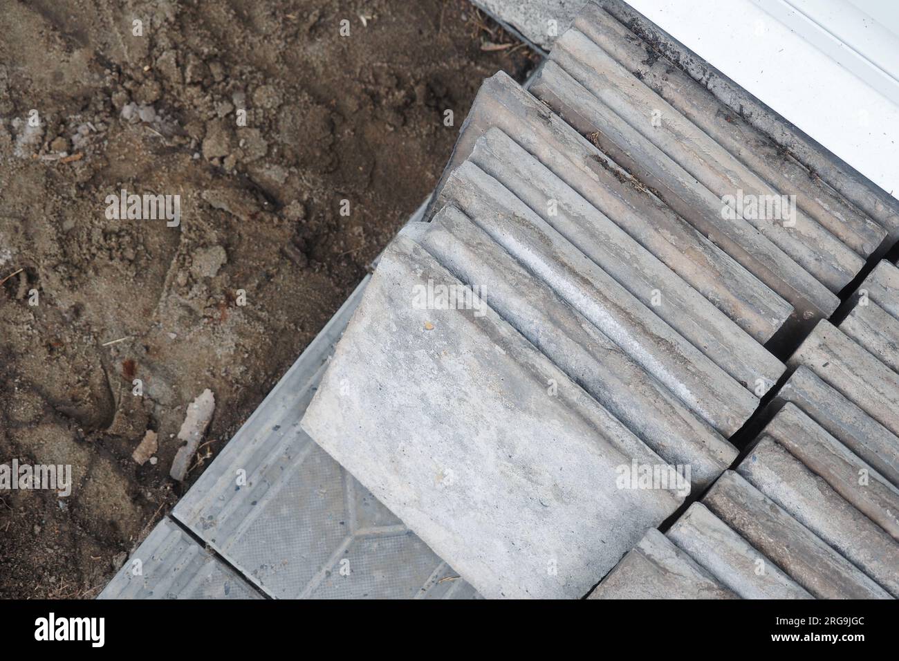 Facing concrete tiles lie on ground in stack. Replacing building ...